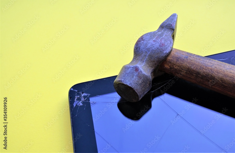 An old hammer with a worn wooden lies next to the tablet with a broken ...