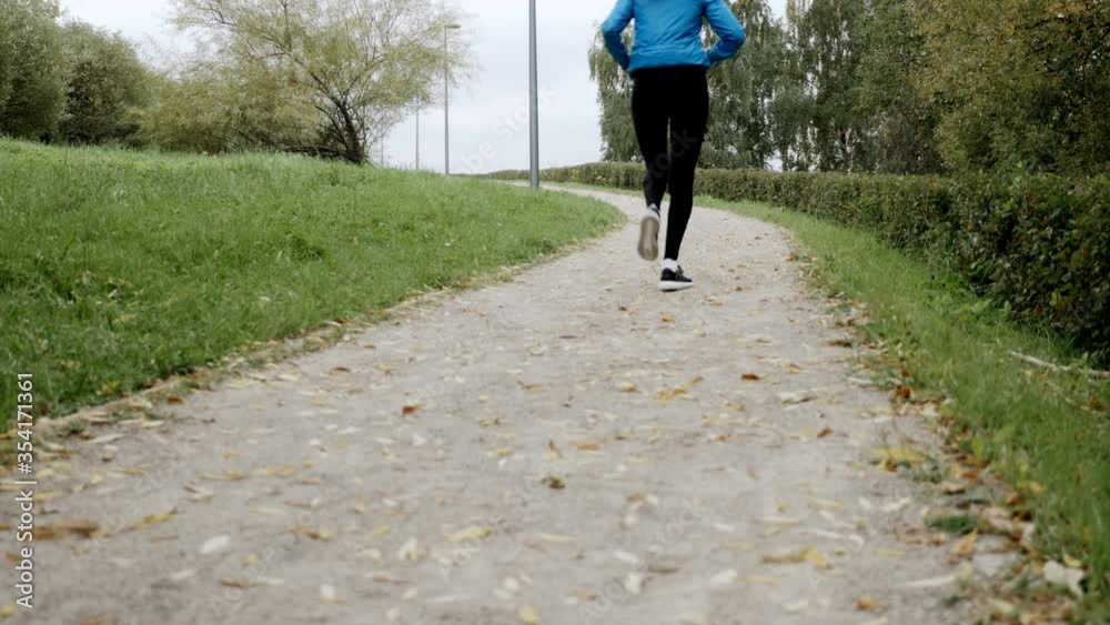 Active woman with a sports figure running along the path in the park ...