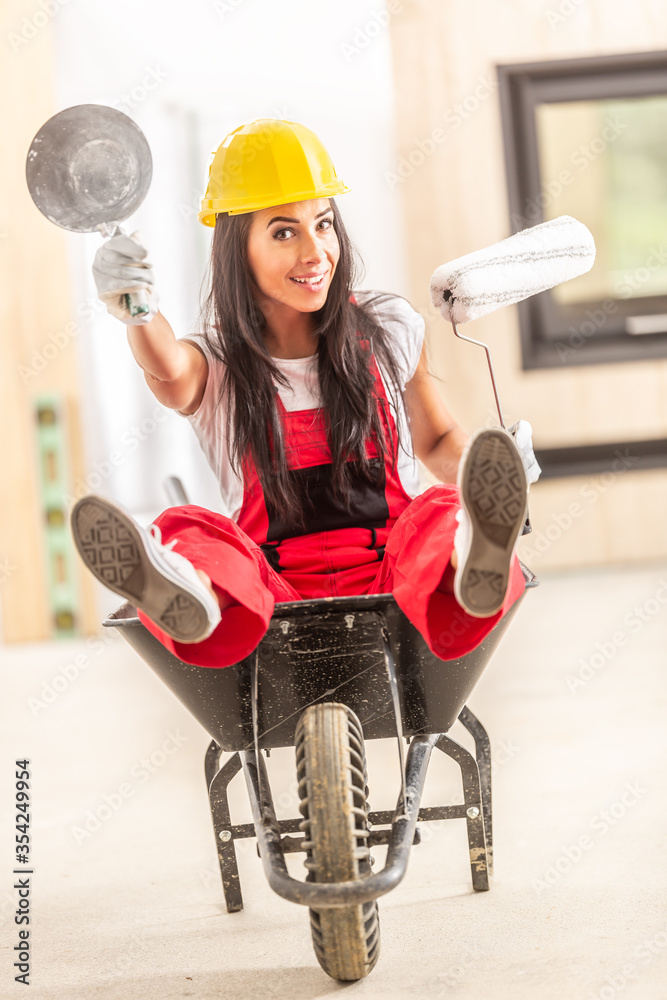 Beautiful girl sitting in a wheelbarrow inside the construction site ...