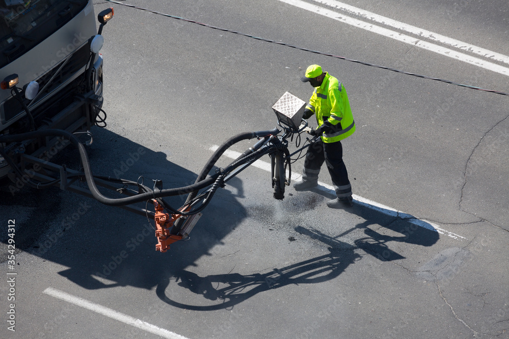 Road surface restoration work. The worker performs on road patcher work ...