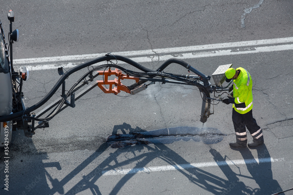 Road surface restoration work. The worker performs on road patcher work ...