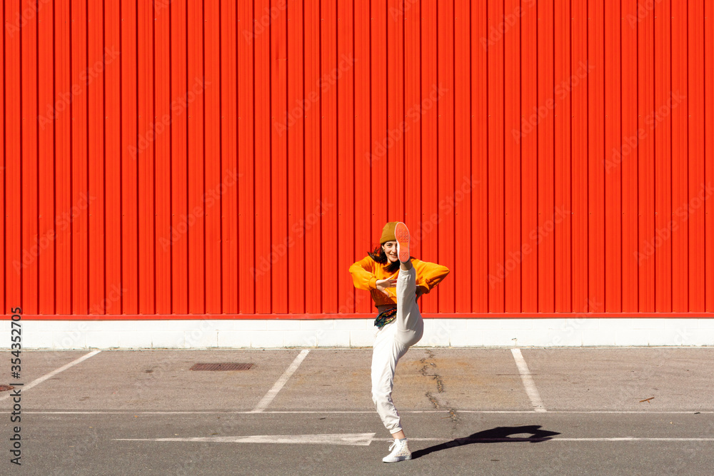 Young woman dancing in front of a red wall Stock Photo | Adobe Stock
