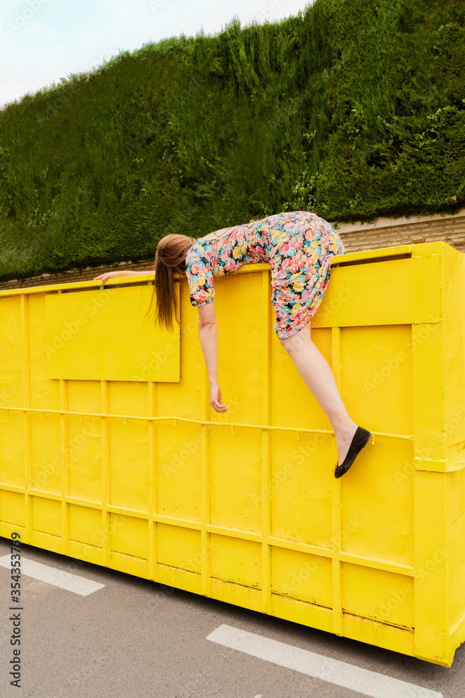 Exhausted woman hanging over edge of yellow container Stock Photo ...