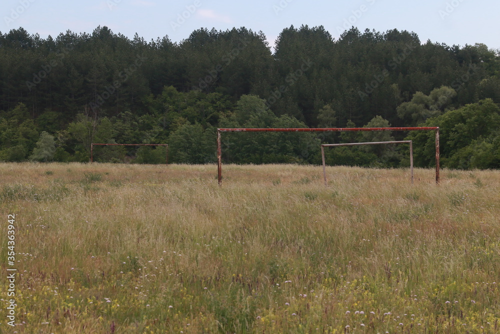 Abandoned football field overgrown with tall grass. Empty football goal ...