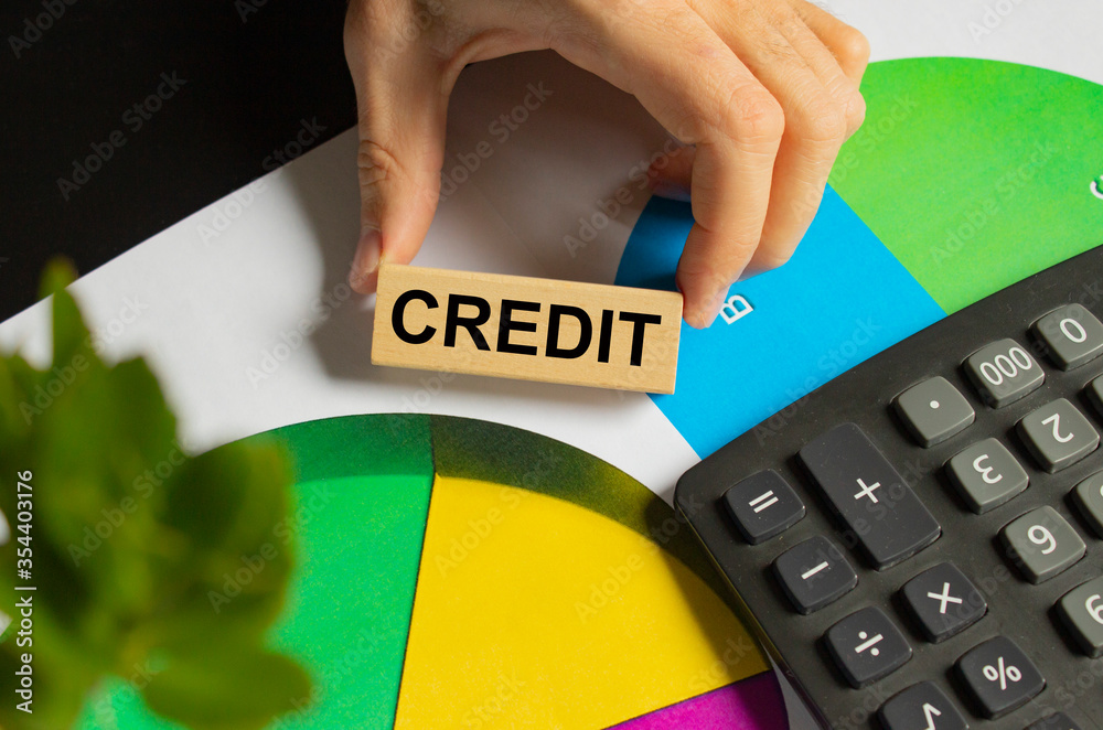 The word credit is written on a wooden block held by a male hand on an ...