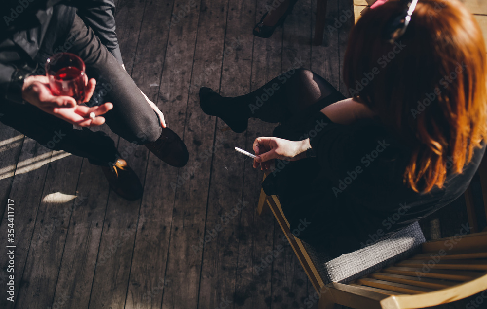 Two people are talking in a smoking room, holding cigarettes and a ...