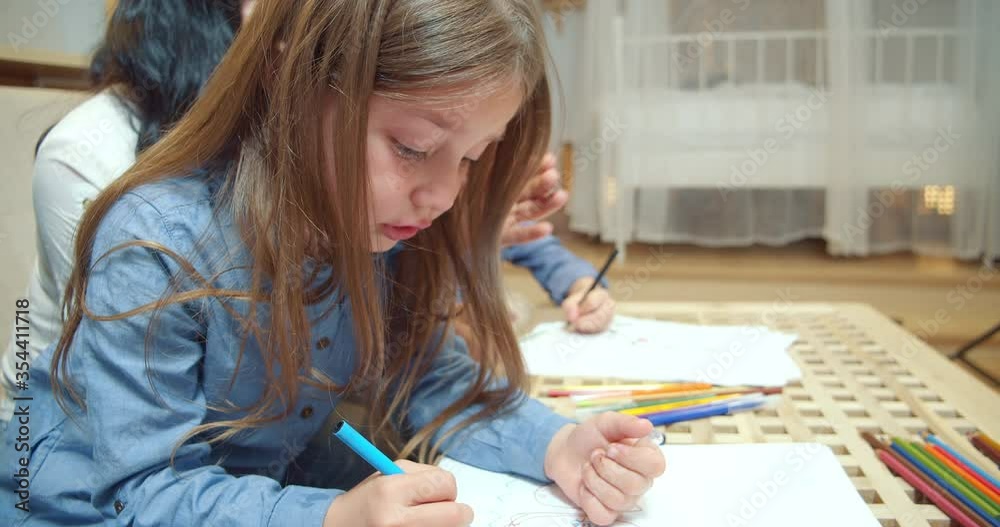 Two cute children and mother drawing with colored pencils and felt-tip ...