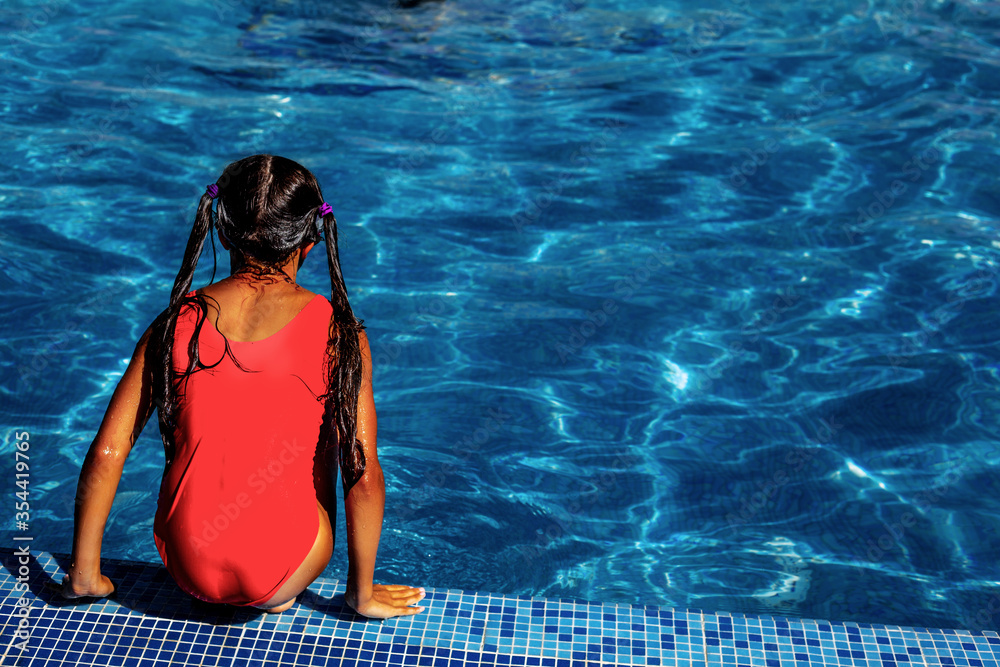 Back view of the preteen girl jumping to dive in the blue water of the ...