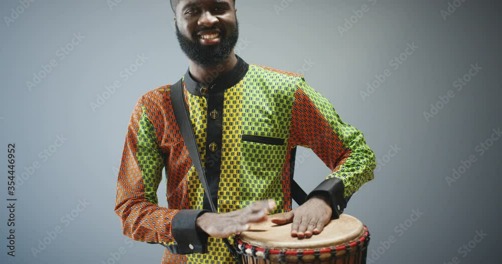 Portrait of male African American musician tapping on drum and smiling ...