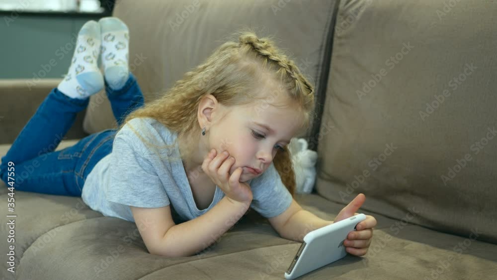 Cute baby having fun with a mobile phone. A little girl in her free ...