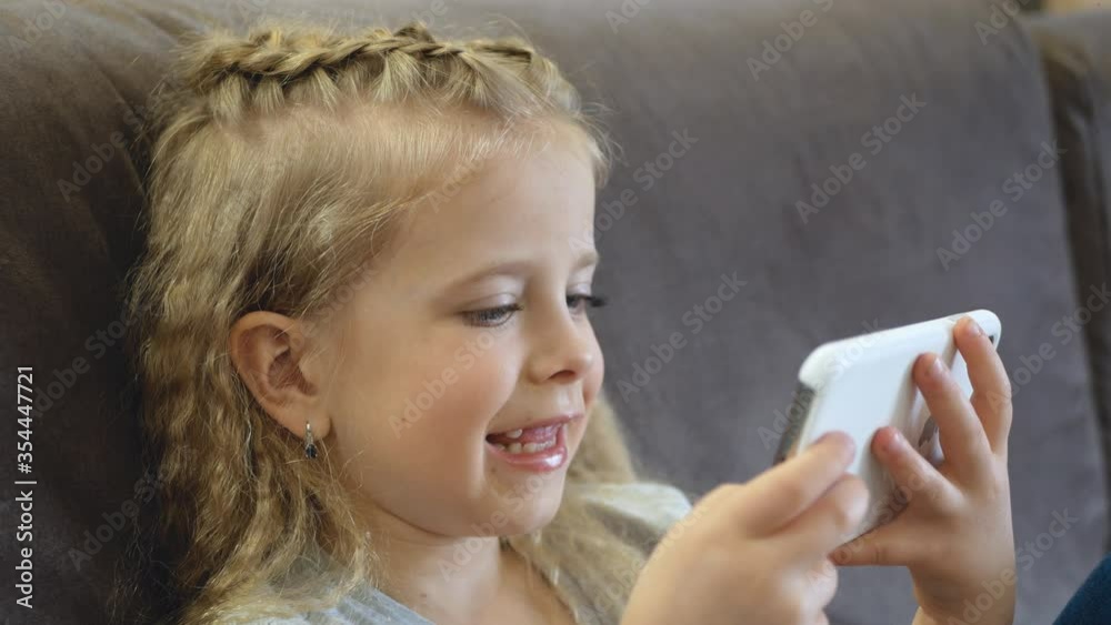 Cute baby having fun with a mobile phone. A little girl in her free ...