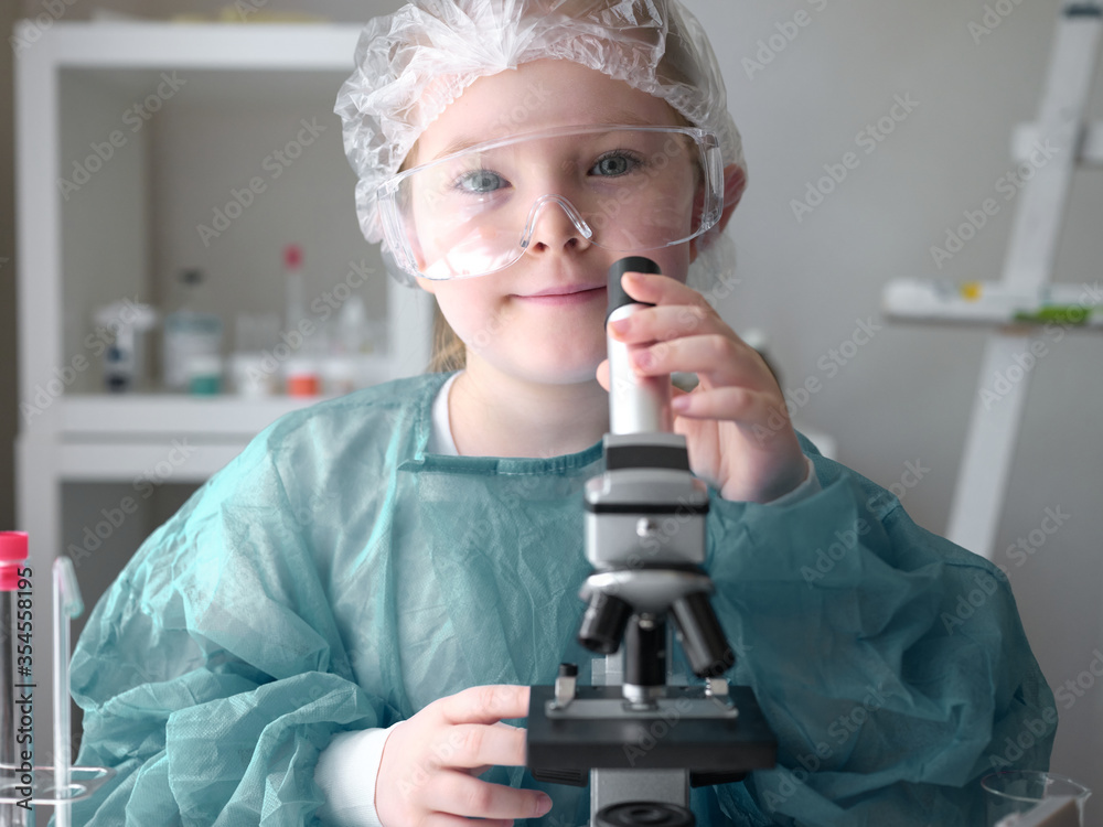 Cute little girl looking into microscope at his desk at home. Young ...