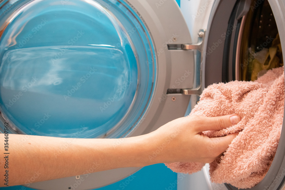 Womans hand puts clothes in a washing machine. Hands to load the ...