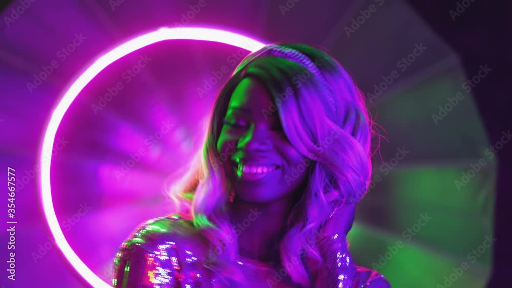 Sensual model posing in neon lights dancing on camera. African American ...