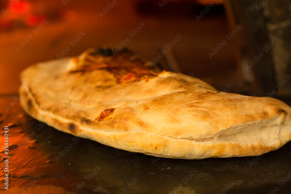 A baker's calzone pizza with a traditional Mediterranean wood-burning ...