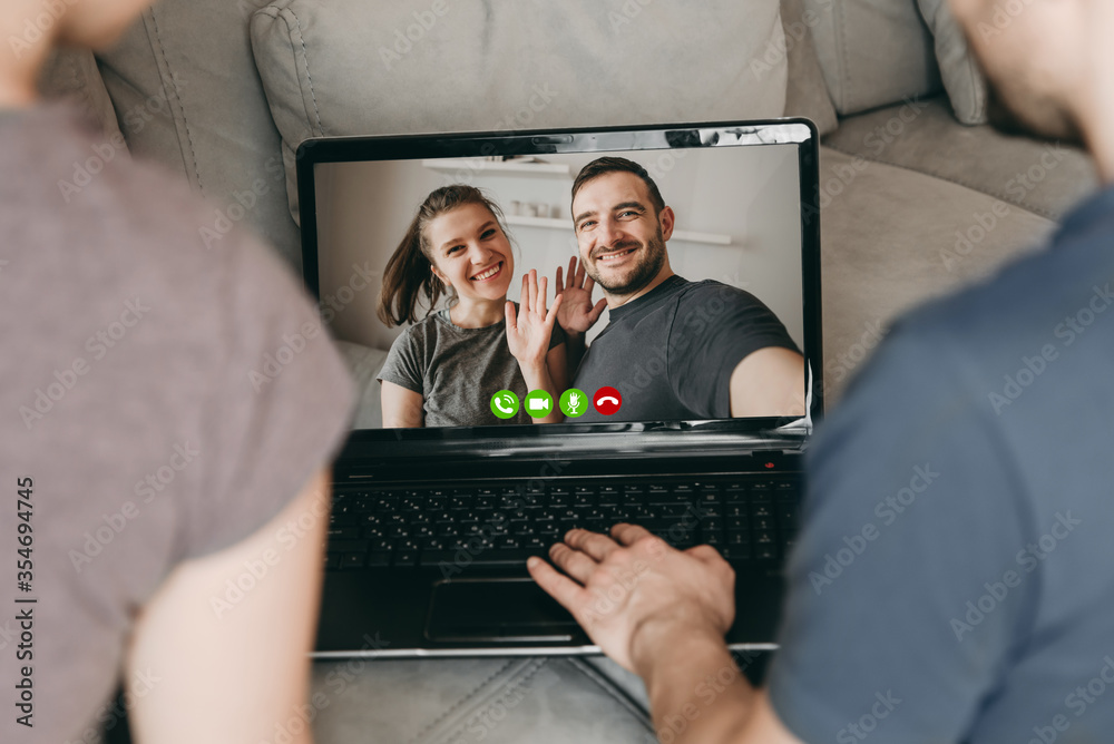 Young happy couple communicates with family through laptop webcam ...