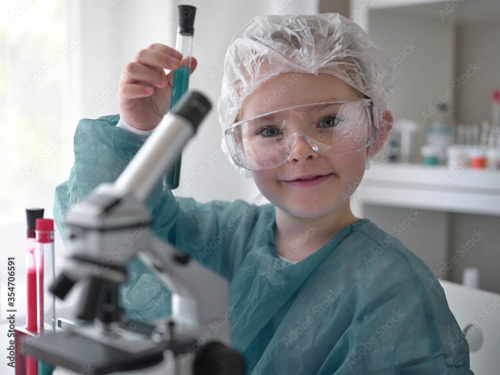 Cute little girl looking into microscope at his desk at home. Young ...