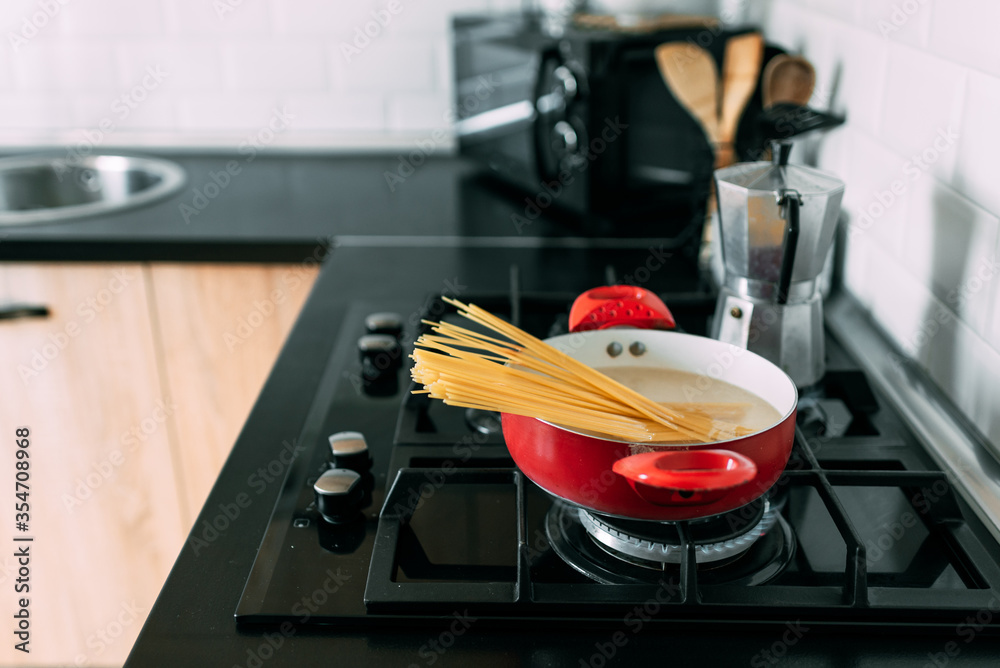 Spaghetti is slowly simmered in a red vintage pot. The brown and black ...