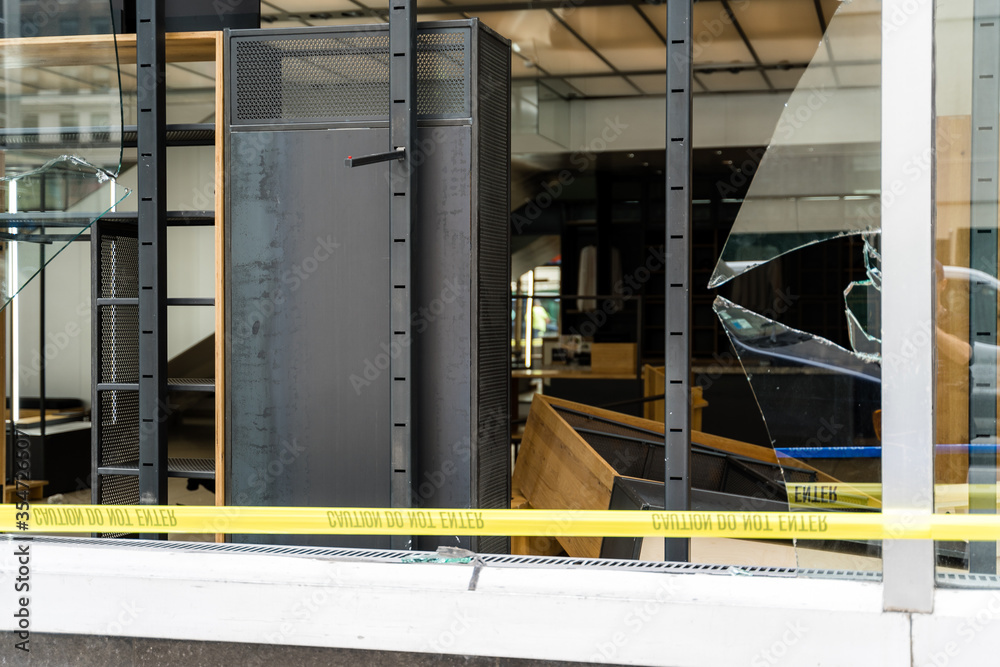 broken window with yellow strip "caution do not enter". damaged store ...
