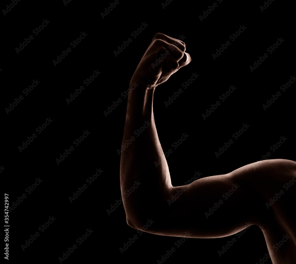 The strong and muscular arm of a black man in front of dark background ...