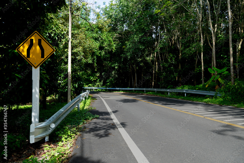 Traffic sign shows the narrow way sign. Beside the asphalt road before ...