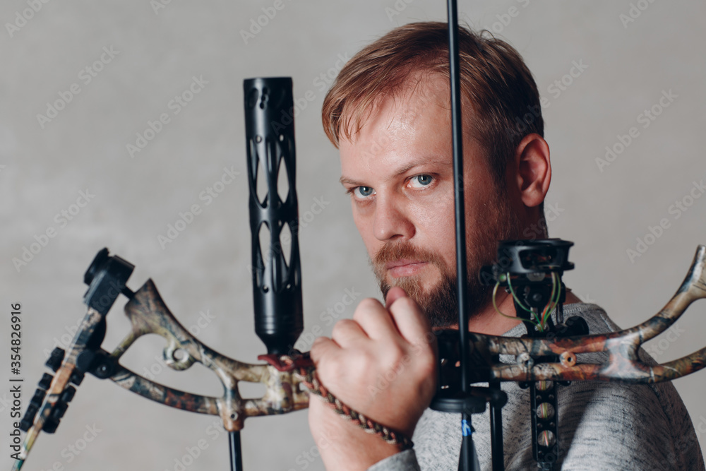 Archer man studio portrait look to camera with modern block sport bow ...