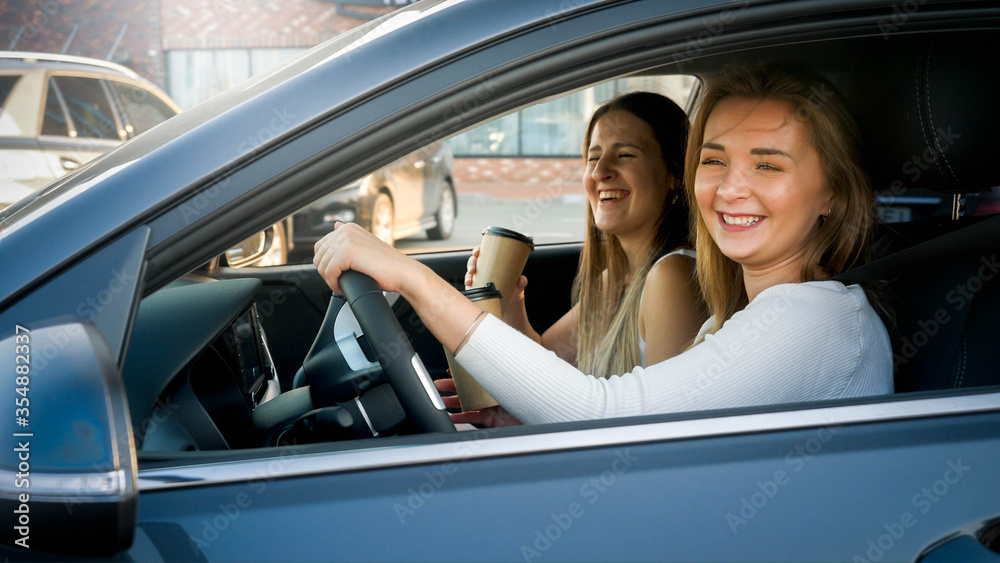 Portrait of happy laughing girls having fun while driving a car in city ...