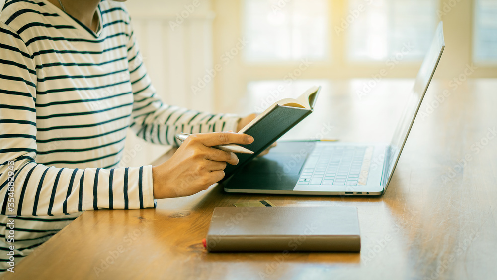 A side view of a young female student reading a book in front of a ...