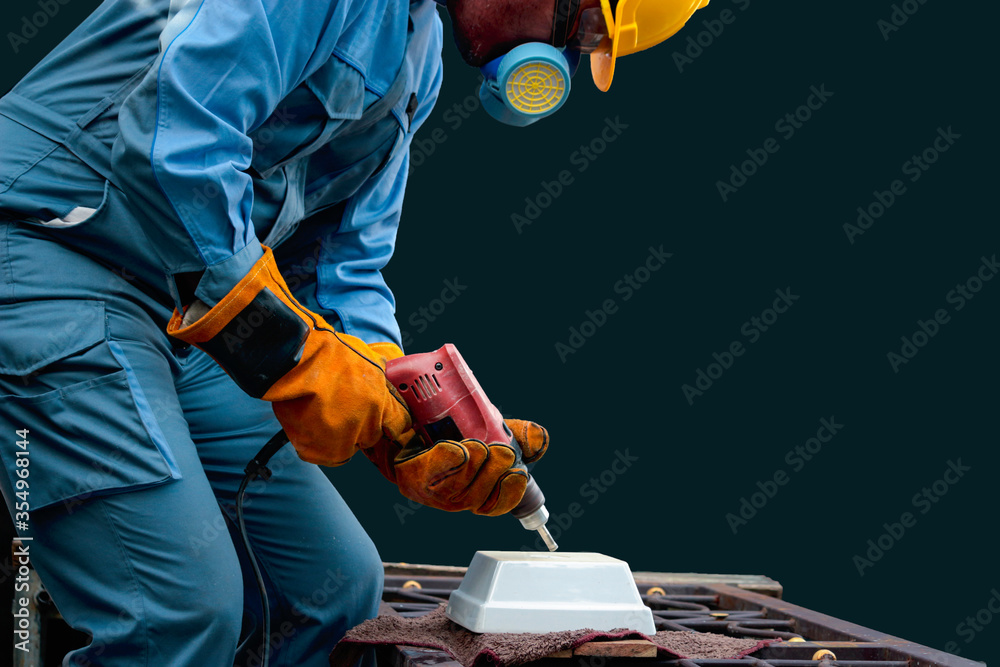 Worker wearing safety equipment, man holding drill, making small hole ...