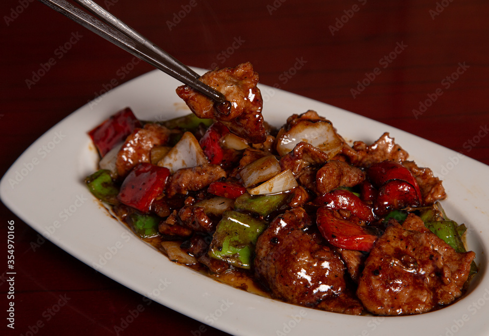 veal dish with peppers in a bean sauce. Chinese chopsticks. isolated ...
