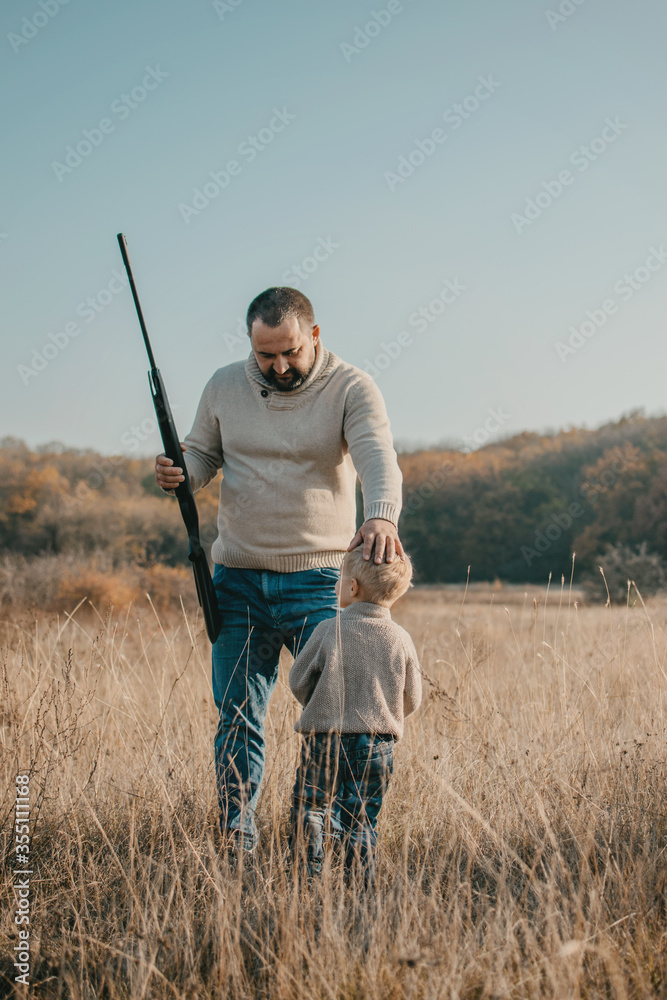 Father's day. Father with gun showing something to son while hunting on ...