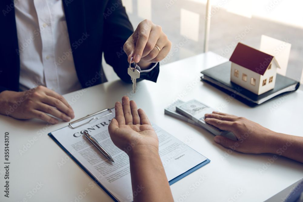 Hand of real estate agent passes the key to new homeowners in office ...