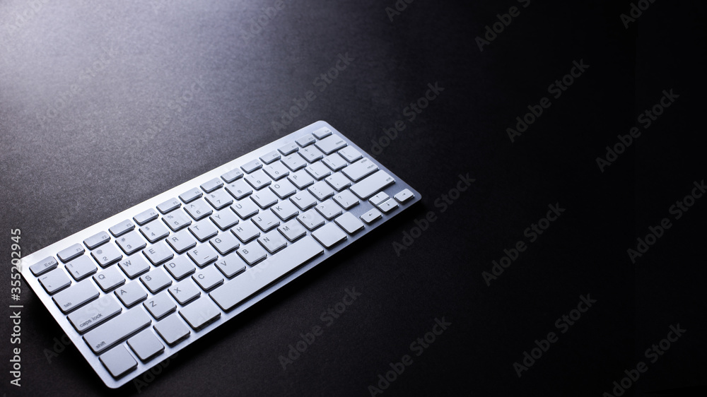 Silver keyboard on black texture background, office desk table from top ...