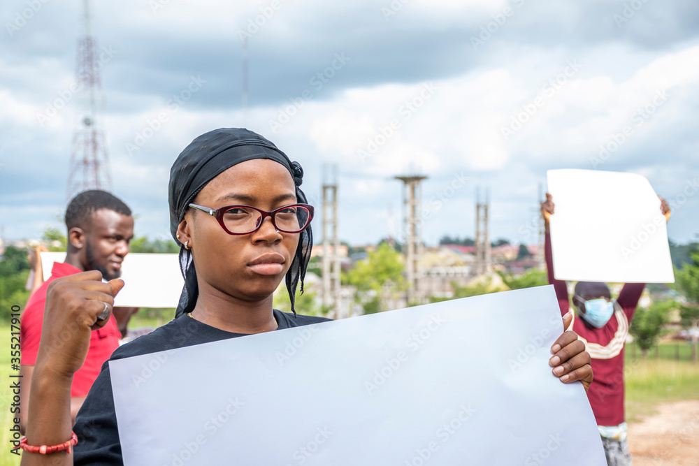 woman in a group of protesting young black african people holding signs ...