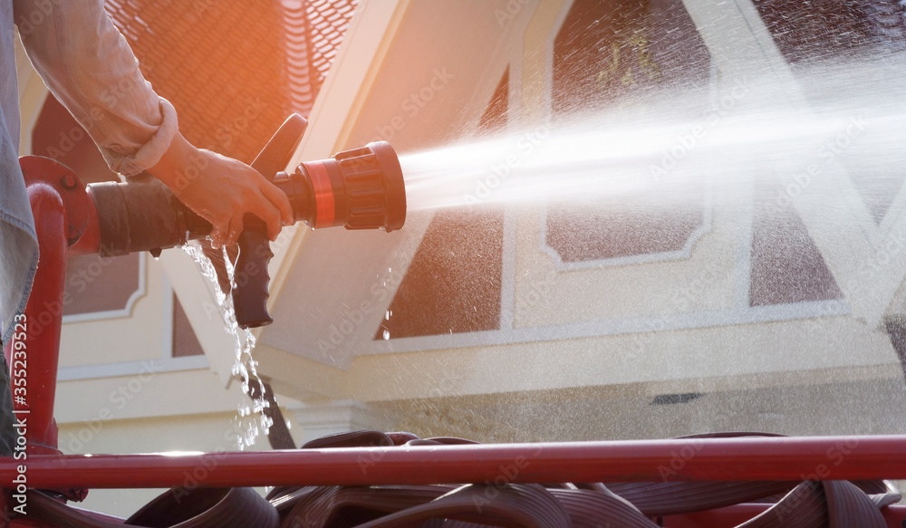 Man's hand using fire fighting nozzle hose on red fire truck to ...