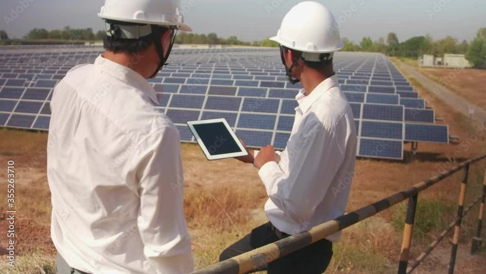 Technician and investor walking in Solar cell Farm through field of ...