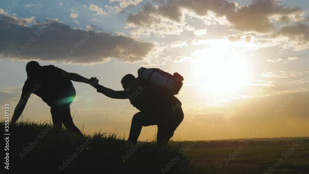 Silhouette of helping hand between two climber. two hikers on top of ...