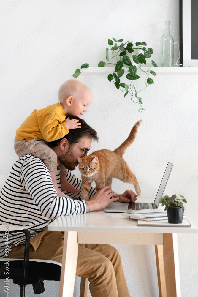 Father working with his baby boy in home office with laptop. Work from ...