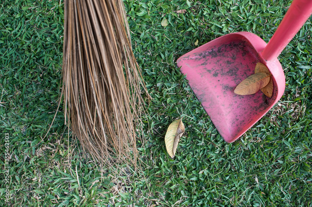 Sweeping leaves off the yard with walis tingting and dustpan. Walis ...