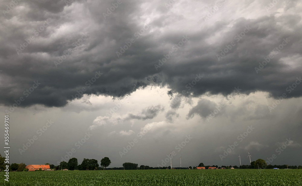 Threatening dark rainy clouds are covering a rural landscape, showing ...