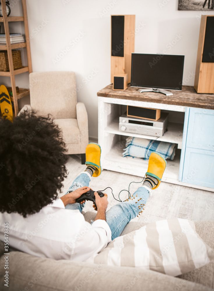 Young man playing computer games sitting at home on couch in front of ...