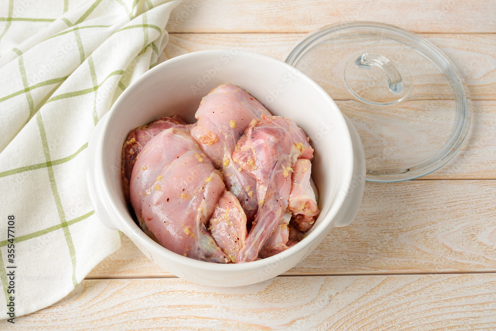 Pieces of fresh raw rabbit meat are marinated with olive oil and garlic ...