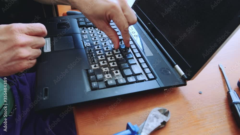 Man breaks the keys of a computer keyboard. Hands that break off ...