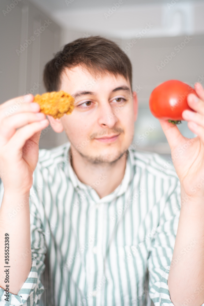 Man chooses between unhealthy and healthy food. The guy holds the ...