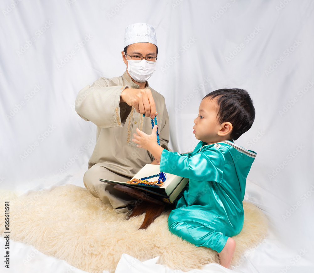 Asian Muslim child and his father in full traditional dress prepare set ...
