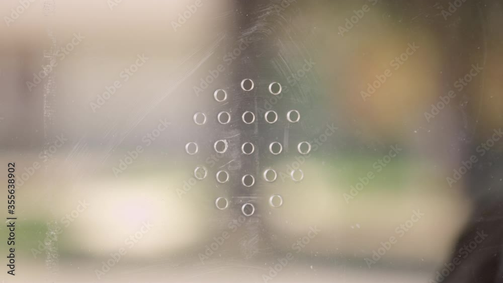 Masked woman speaks through holes in plexiglass window at a charity ...