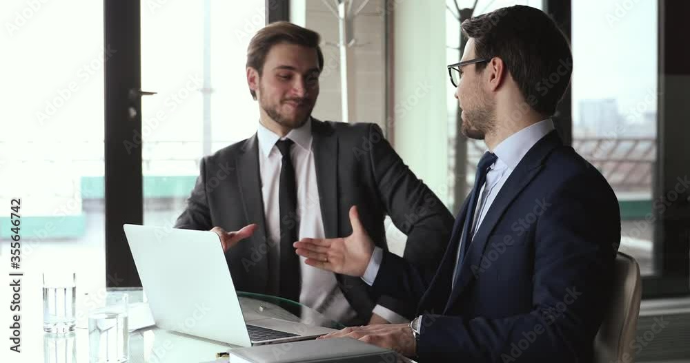 Two smiling male business partners handshake use laptop find ...