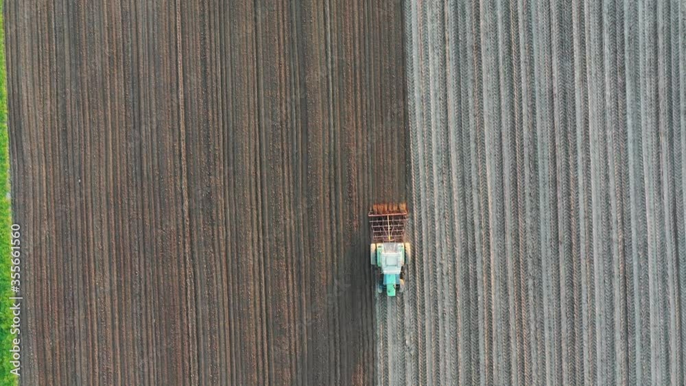A farmer plowing his field with a tractor during spring, seen from ...