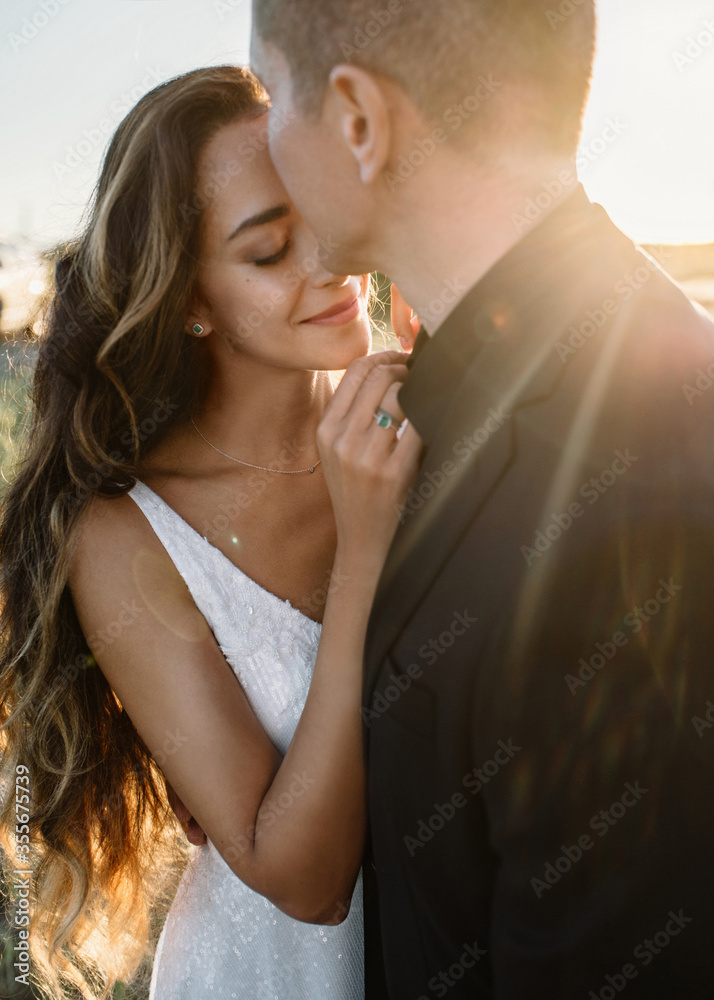 Sensual wedding couple hugging and smile. Handsome groom gently kisses ...