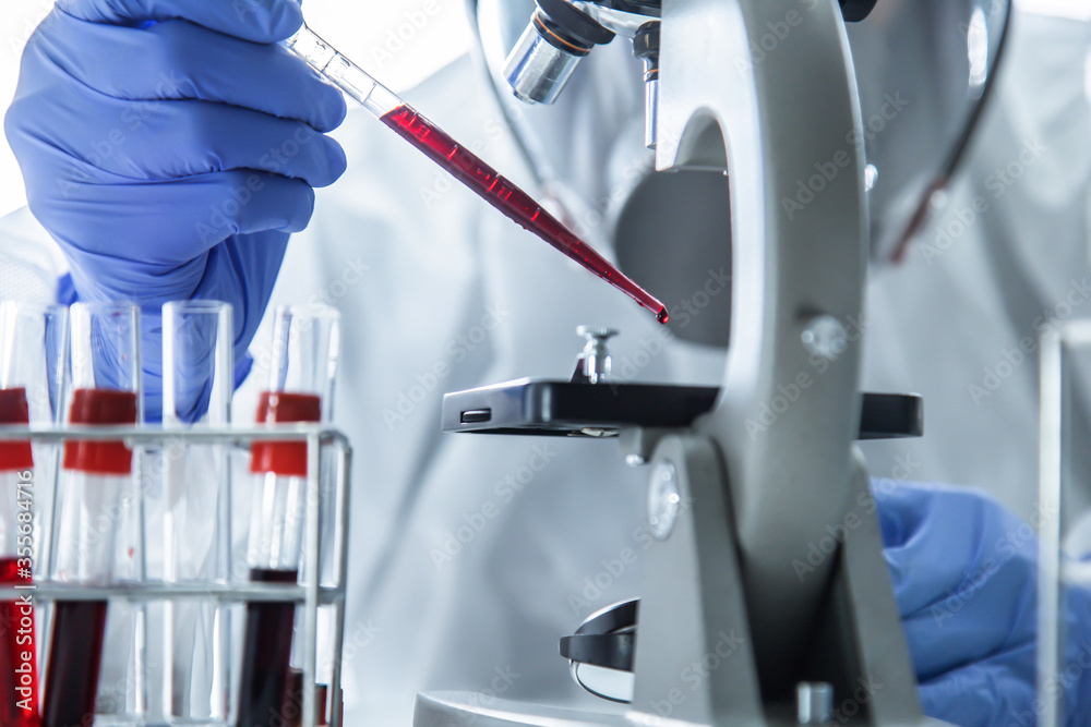 Lab technician analyzing a blood sample in test tube at laboratory with ...